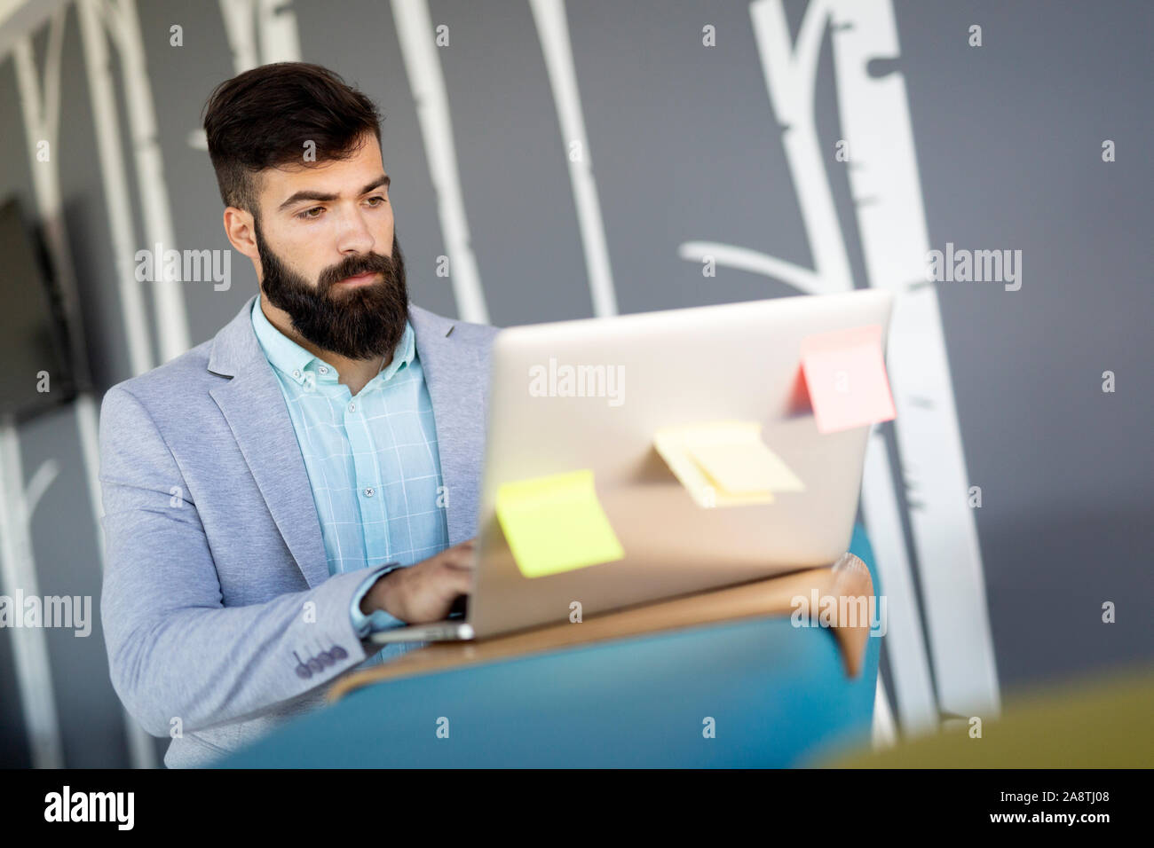Portrait of young man sitting at desk in the office Stock Photo - Alamy