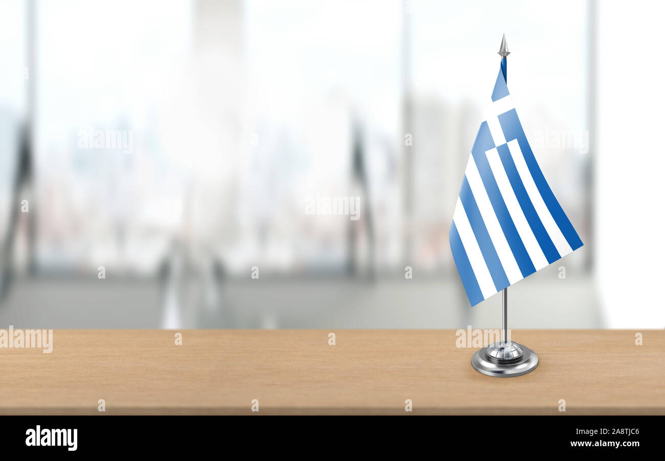 Greek flag is standing on a metal pole is at wooden office table. High ...