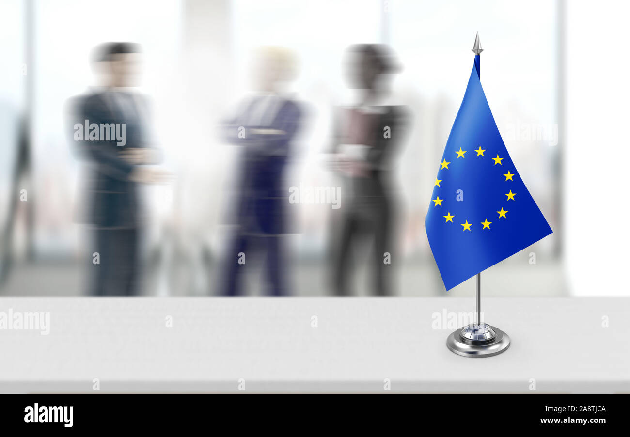 European Union flag is standing on a metal pole is at office table ...