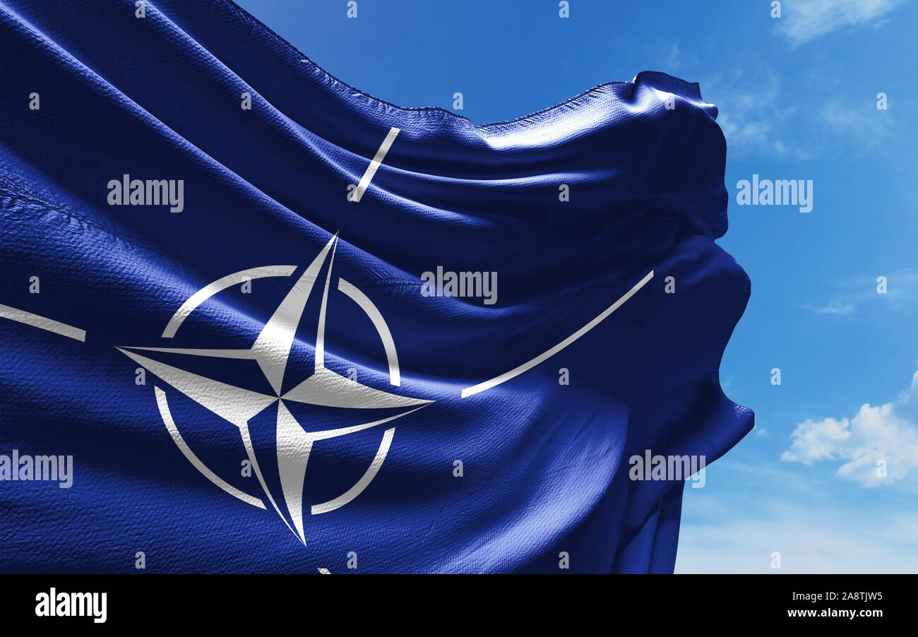 NATO flag is waving against blue sky with clouds. Realistic reflections ...