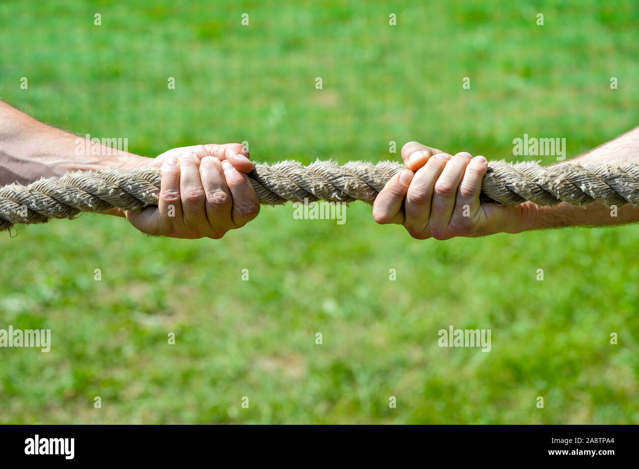 Two men's hands pull the rope each in his own direction. The concept of ...