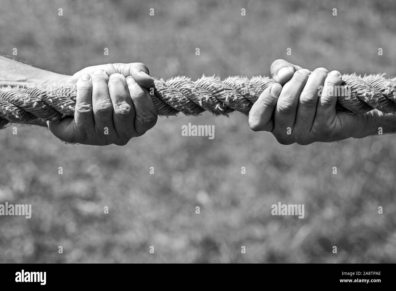 Two men's hands pull the rope each in his own direction. The concept of ...