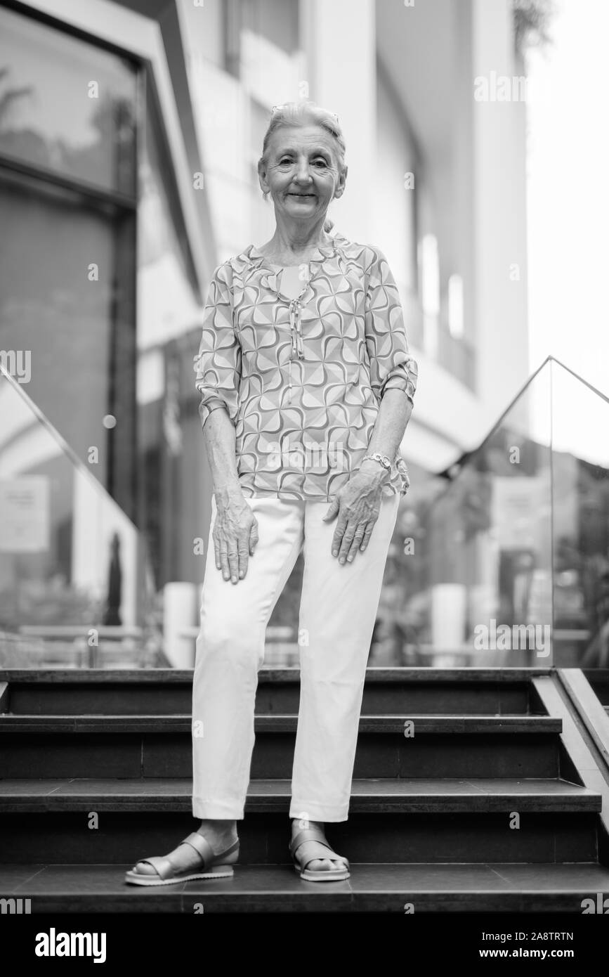 Beautiful senior tourist woman relaxing around the city in black and ...
