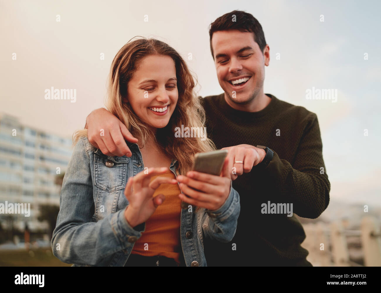 Smiling young group of friends using mobile device apps, surfing ...