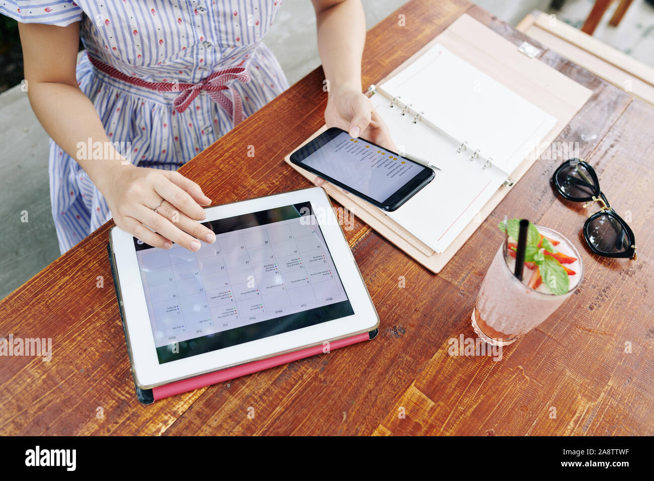 Hands of young woman checking calendar on her tablet computer and ...