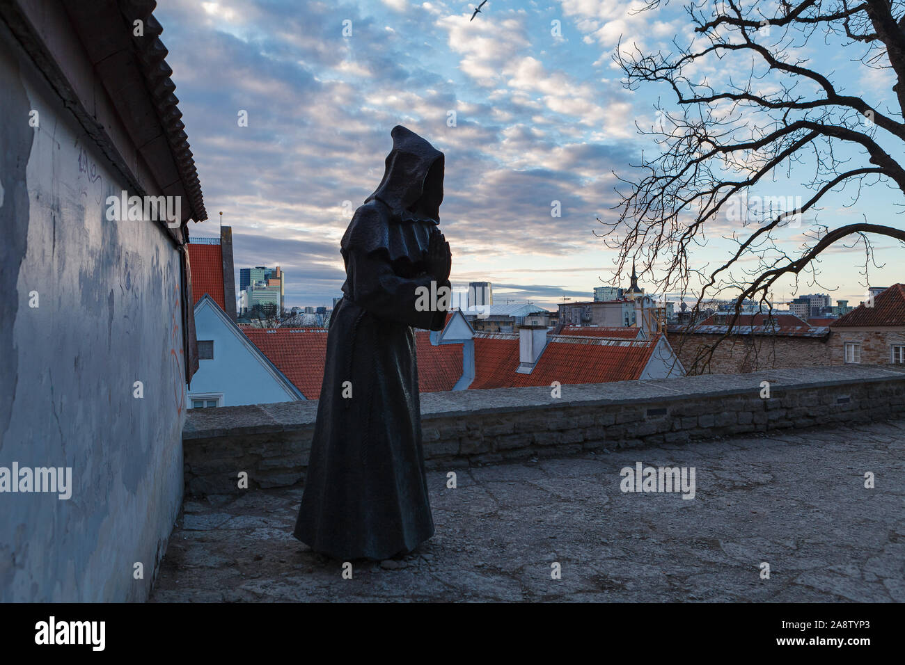 Monk sculpture in Danish King Garden against red roofs and cloudy sky ...