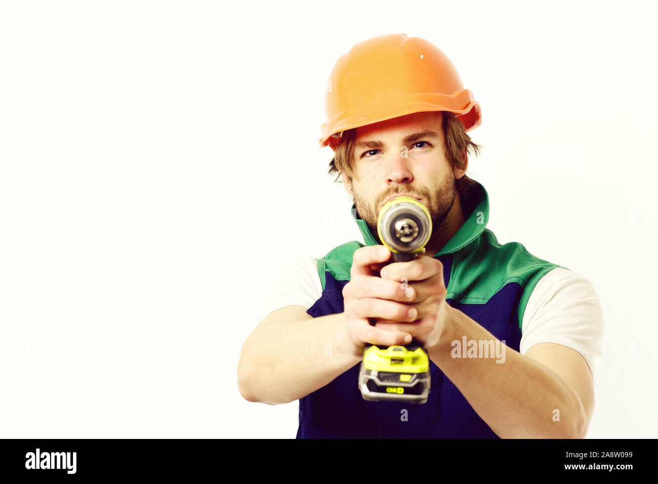 Construction worker holds yellow drill as gun. Builder in orange helmet ...