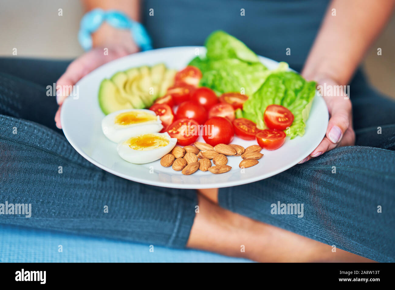 Adult woman eating healthy lunch and sitting on yoga mat Stock Photo ...