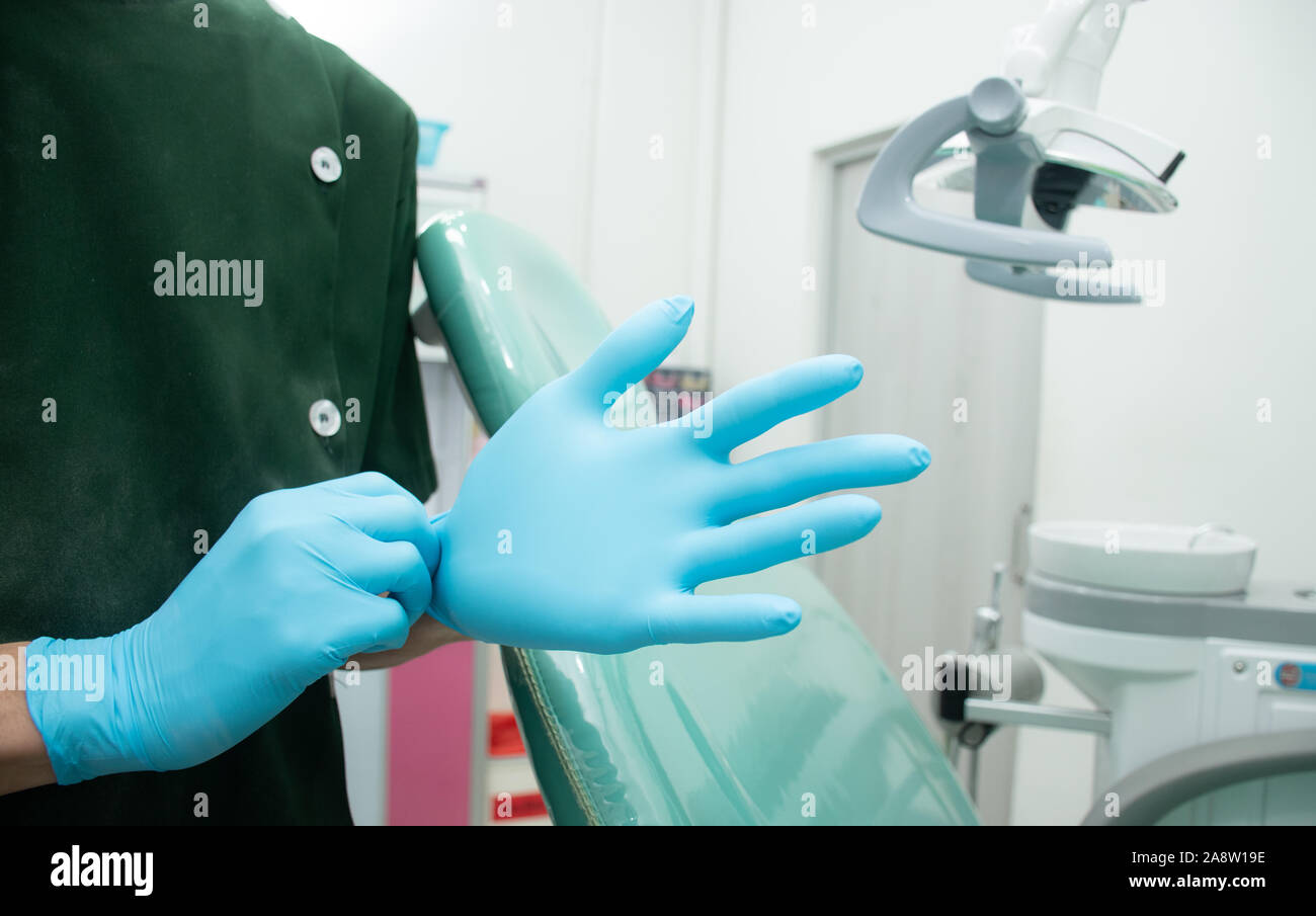 Male dentist in green uniform wear blue rubber gloves for cleanliness ...