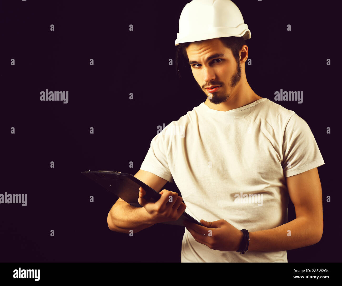 handsome bearded builder or foreman in white shirt and helmet on ...