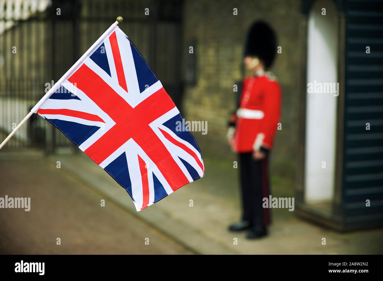 British Union Jack flag flying in front of unrecognizable royal guard ...