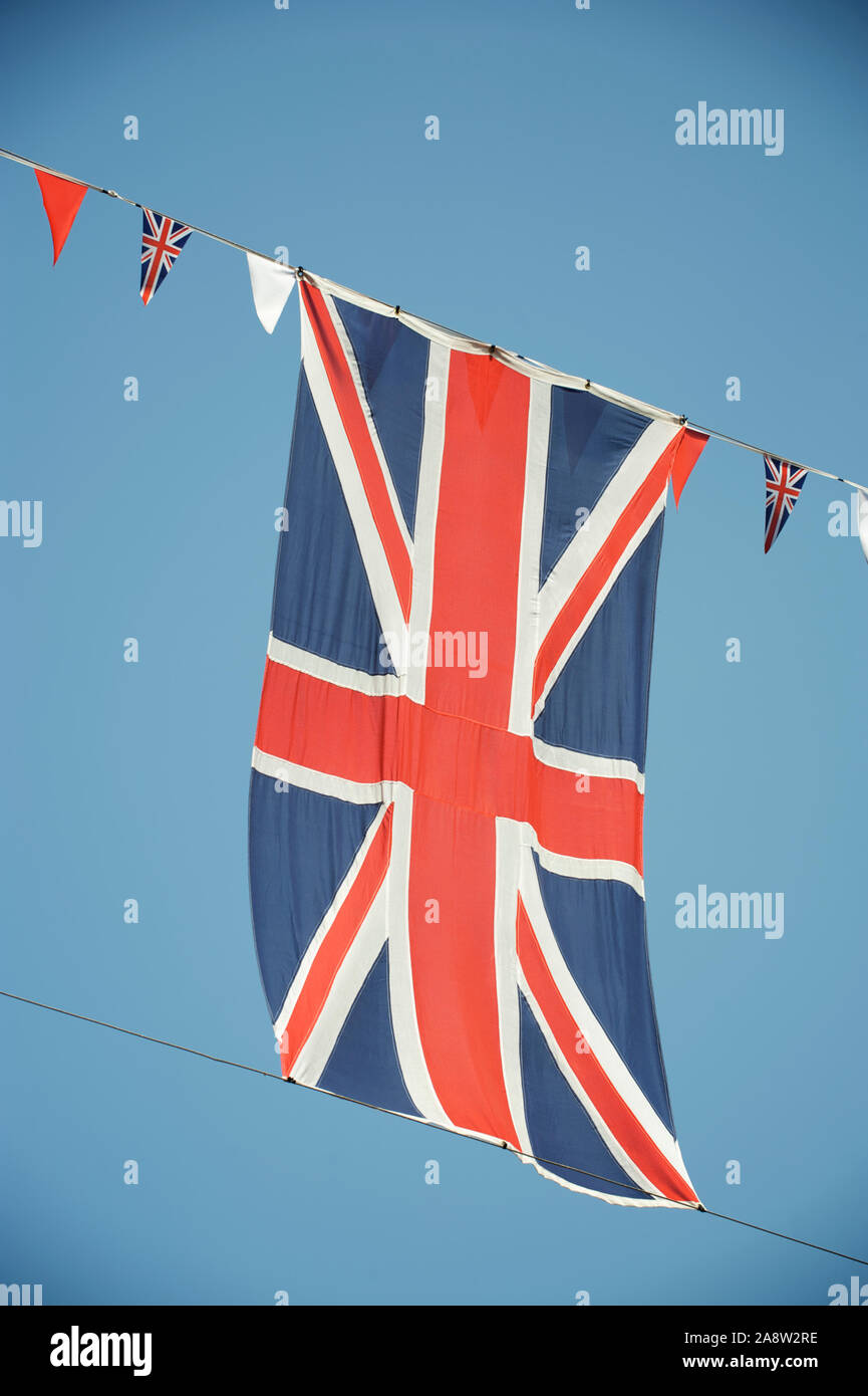 Single Union Jack British flag hanging vertically in soft blue sky ...