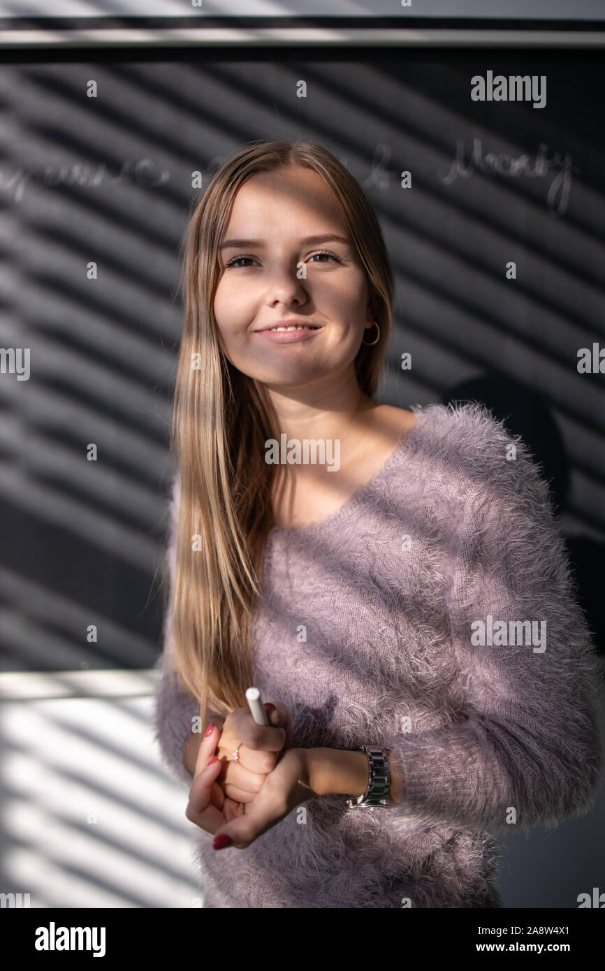 Pretty, young female student/teacher in front of a blackboard during ...