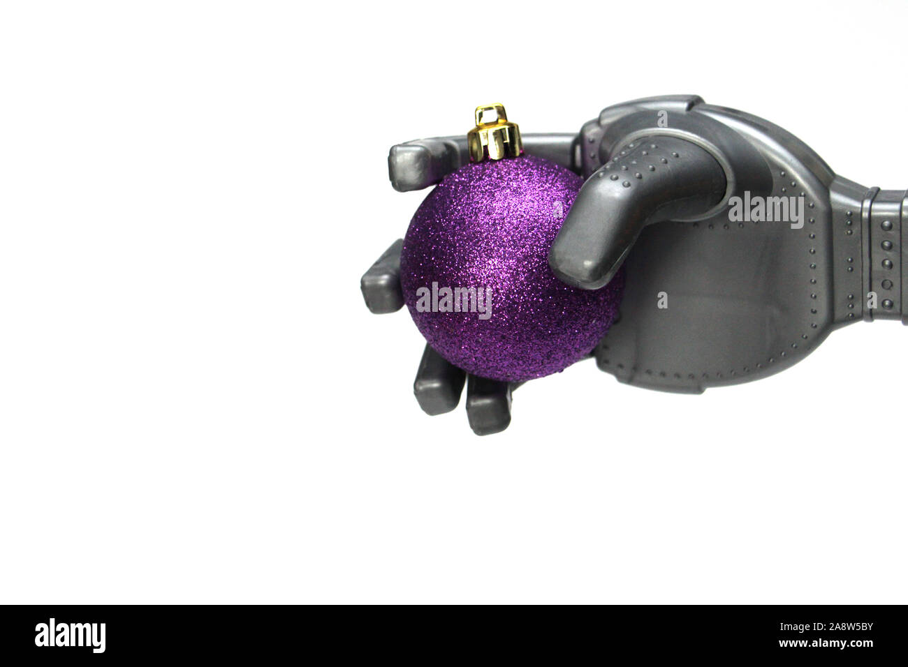 A robot holds a purple Christmas tree decoration in his hand. Purple ...