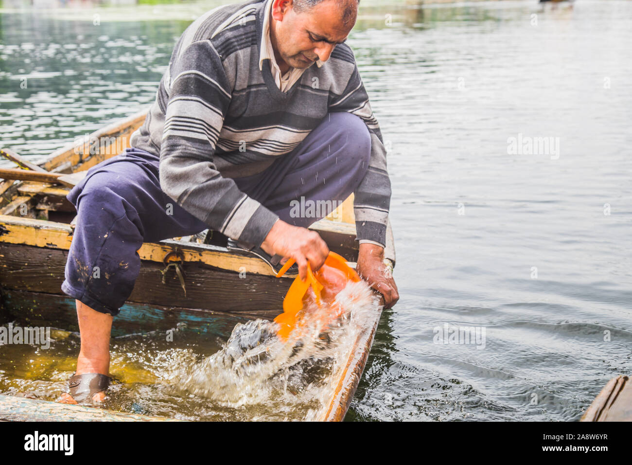 An old man removing water which has entered the broken boat Stock Photo ...