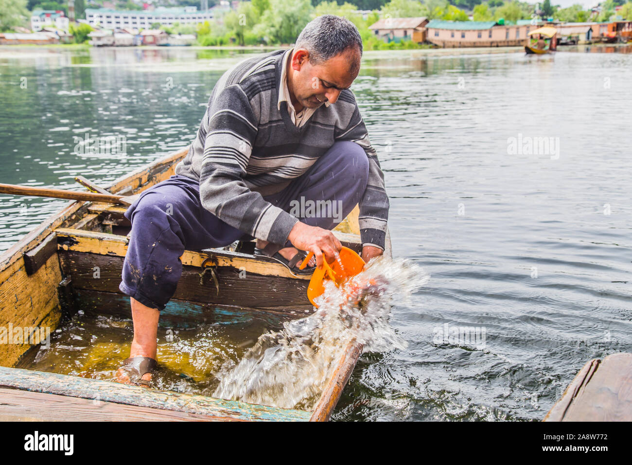 An old man removing water which has entered the broken boat Stock Photo ...
