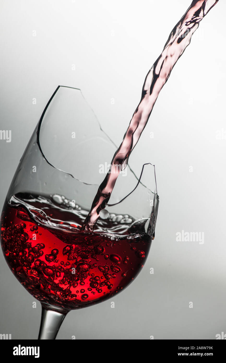 Studio closeup of filling a broken red wine glass against textured ...