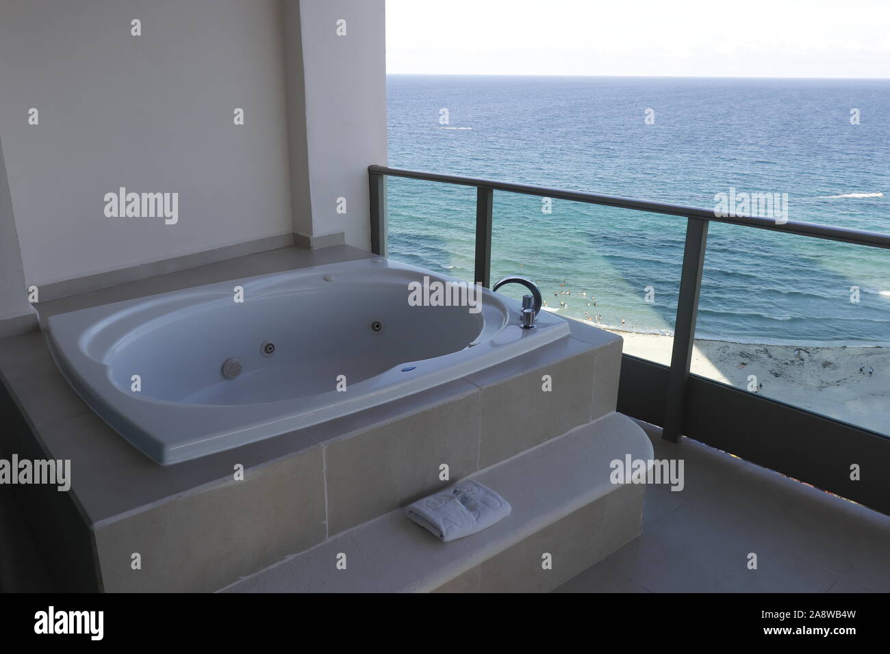 Empty jacuzzi with running water and white towels facing a beach with a ...