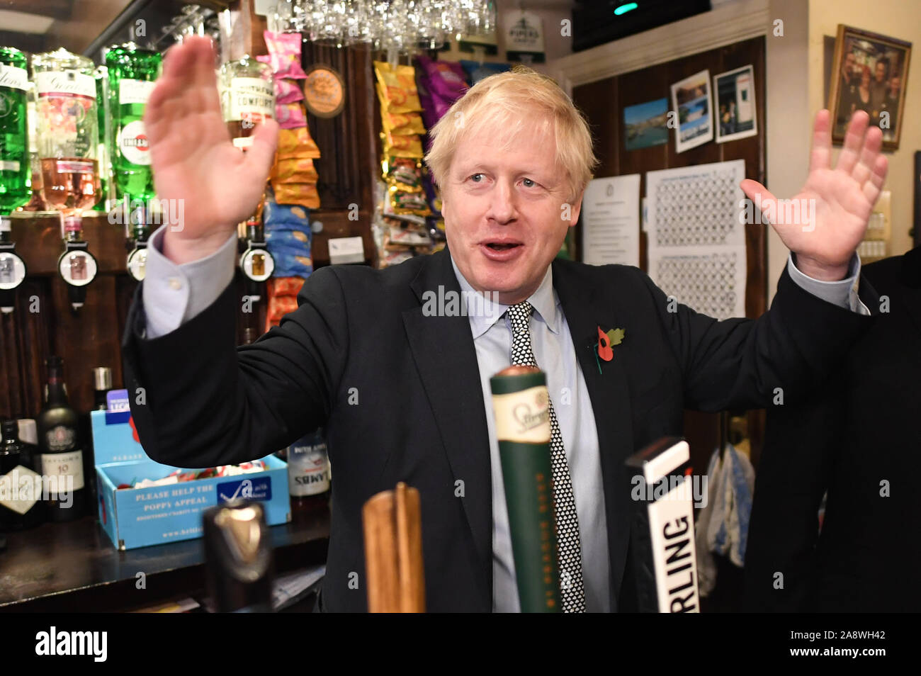 Prime Minister Boris Johnson, steps behind the bar to pull a pint as he ...