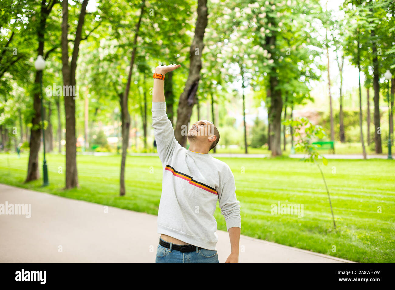 Man holding something up by one hand in the park Stock Photo - Alamy