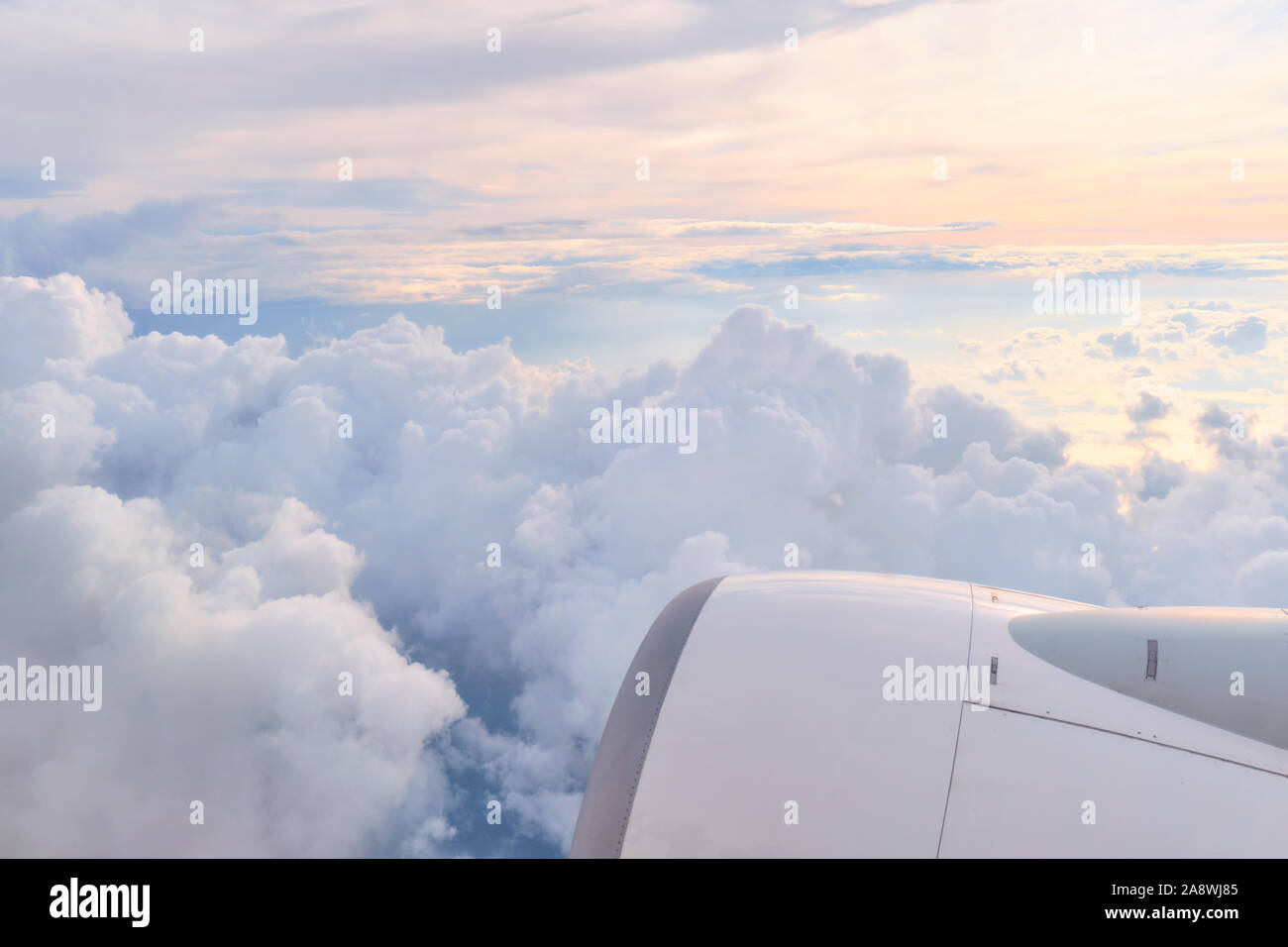 Airplane jet engine in fluffy white clouds with orange and light blue ...