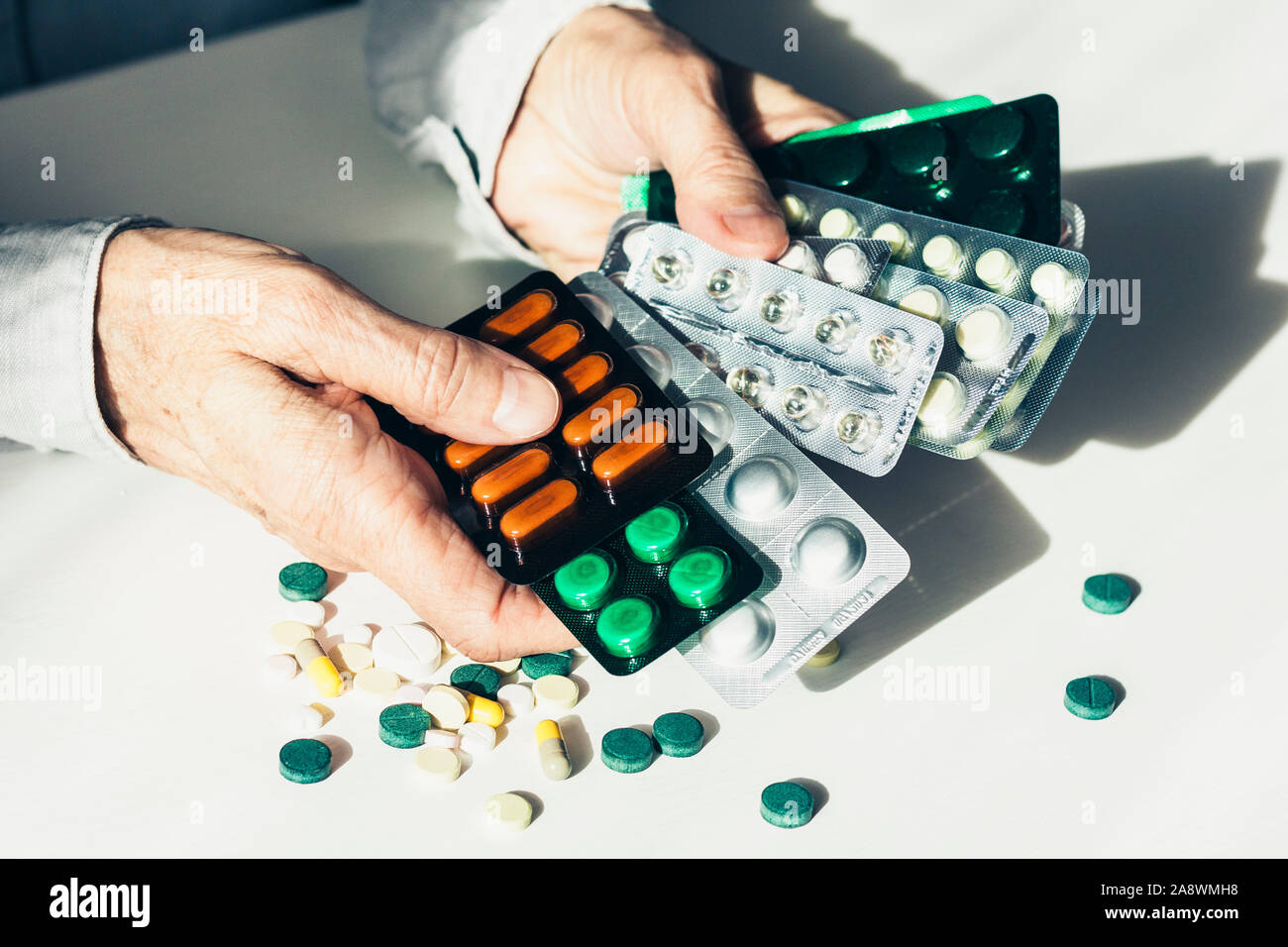 Medicine pills or capsules in blister with old woman’s hands on white ...