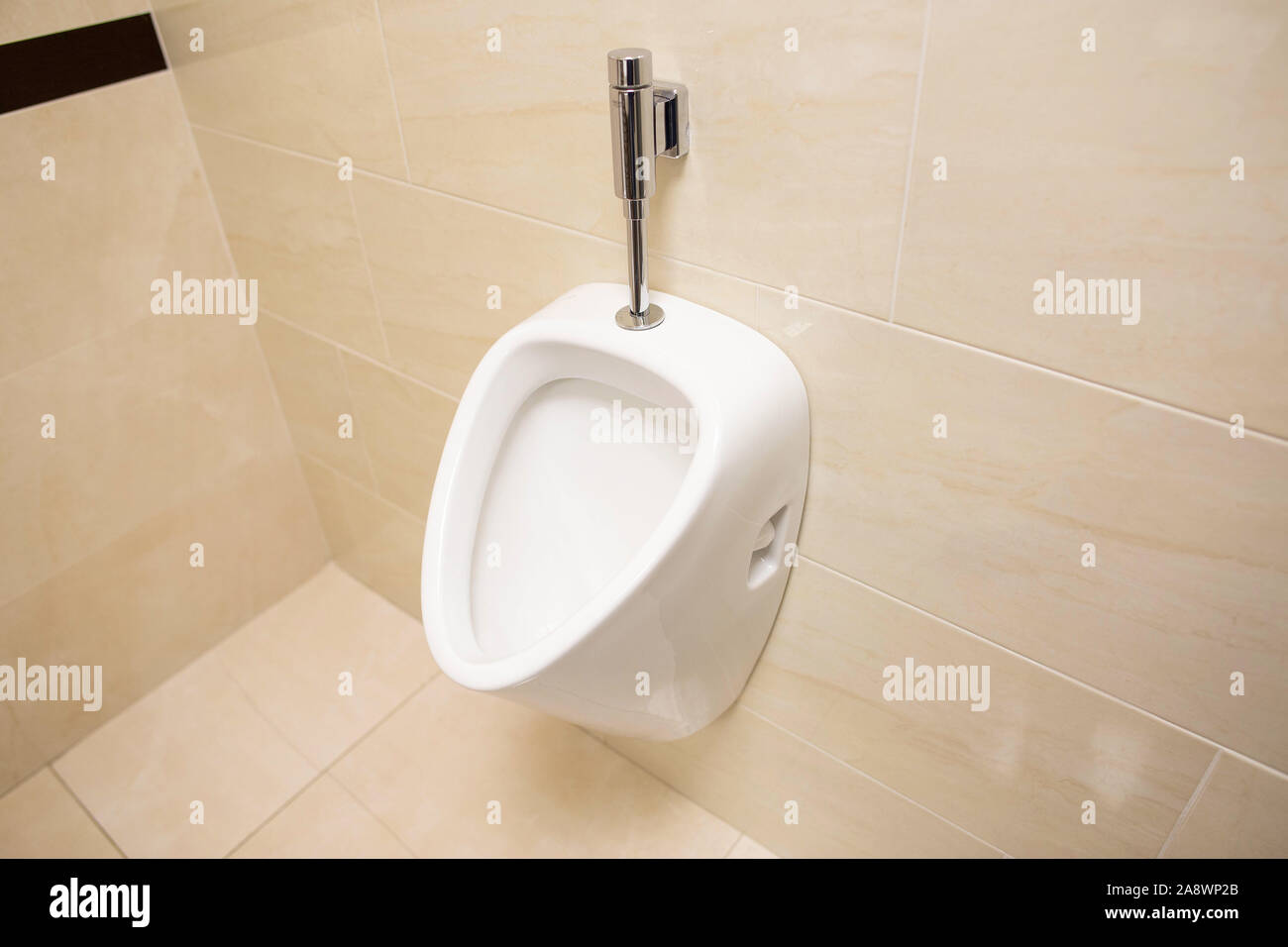 Modern stylish male urinal on the wall. Beautiful brown ceramic tile ...