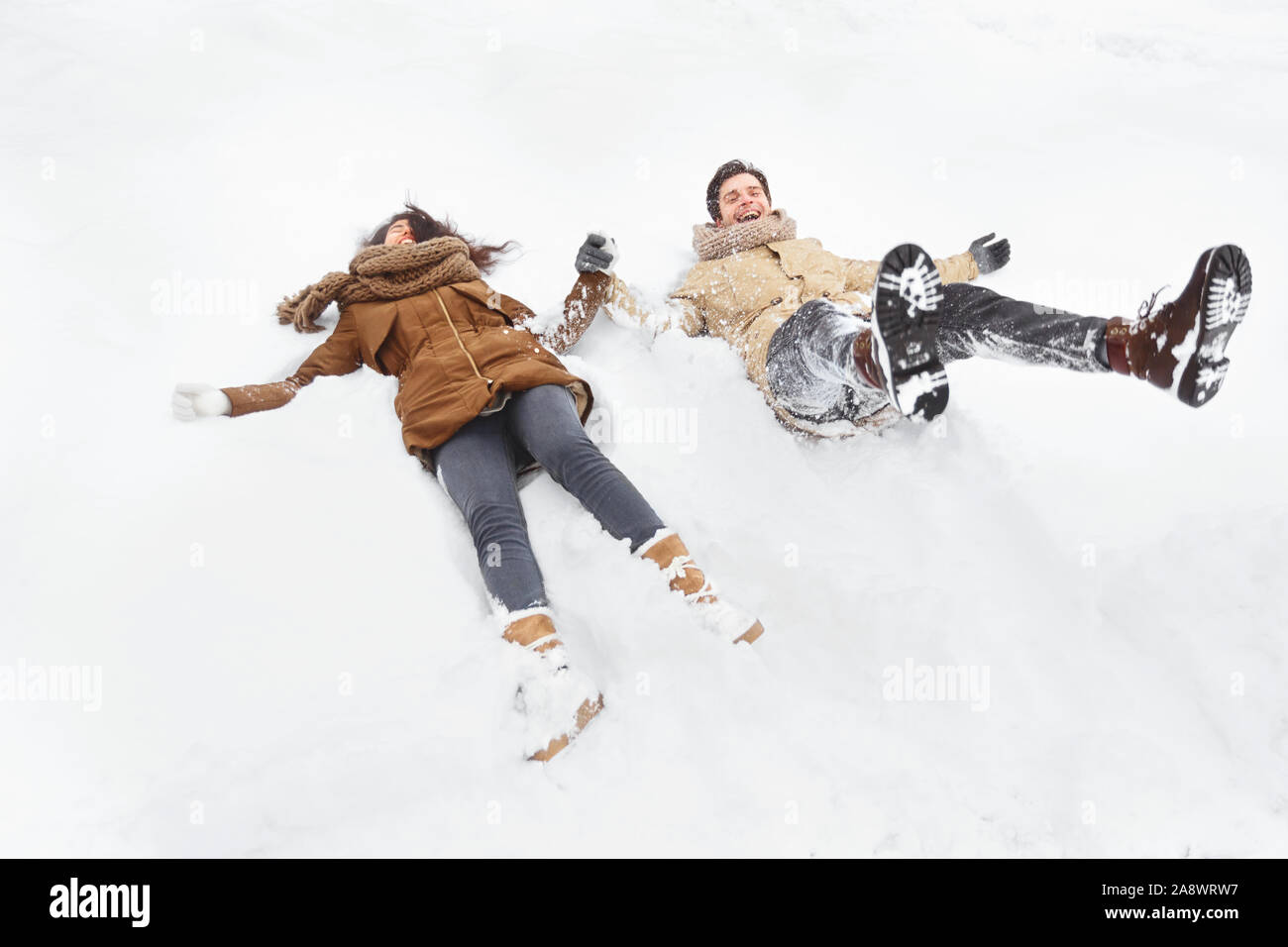 Couple Lying In Snow And Laughing Having Fun Outdoor Stock Photo - Alamy