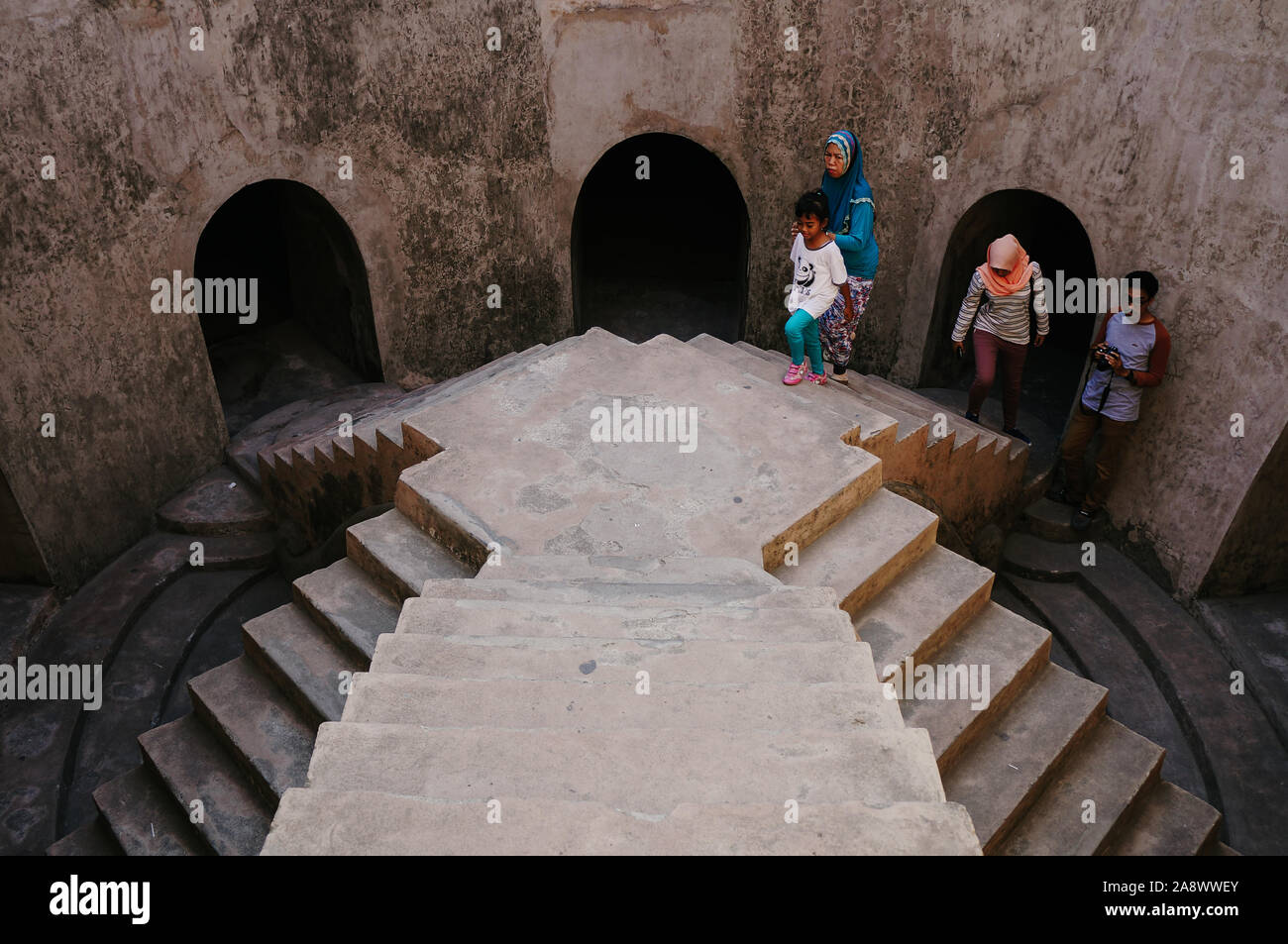 Tourists walk up the stairs over Sumur Gumuling site around Tamansari ...