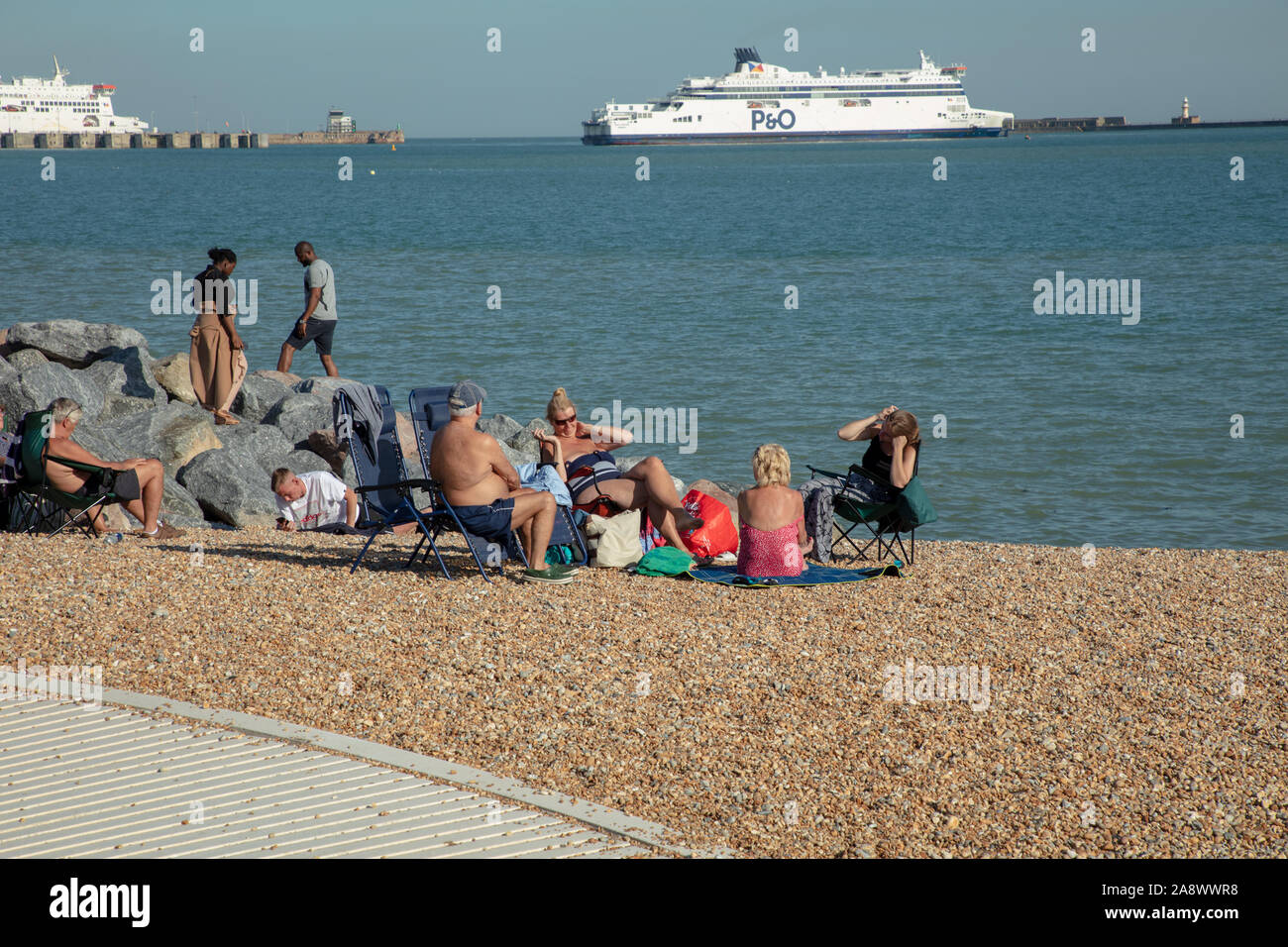 People enjoying the beach at Dover harbour on a warm sunny late ...