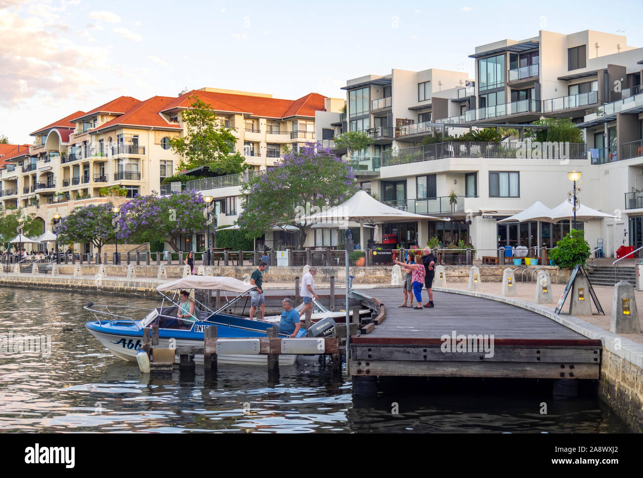 People boarding a boat in Claisebrook Cove, Jacaranda trees and high ...