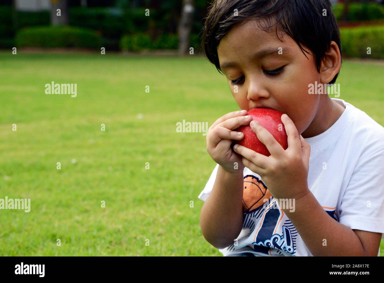 Small boy Biting an apple Stock Photo - Alamy
