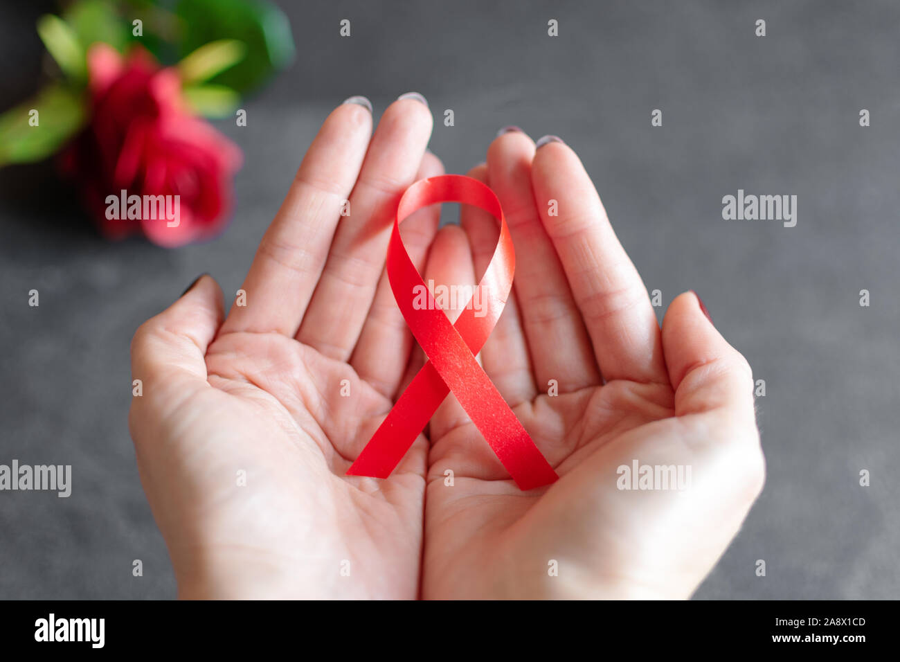 Female hand holding red ribbon as a symbol of World aids day December 1, campaign help people ...