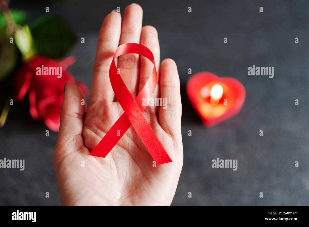 Female hand holding red ribbon as a symbol of World aids day December 1, campaign help people ...