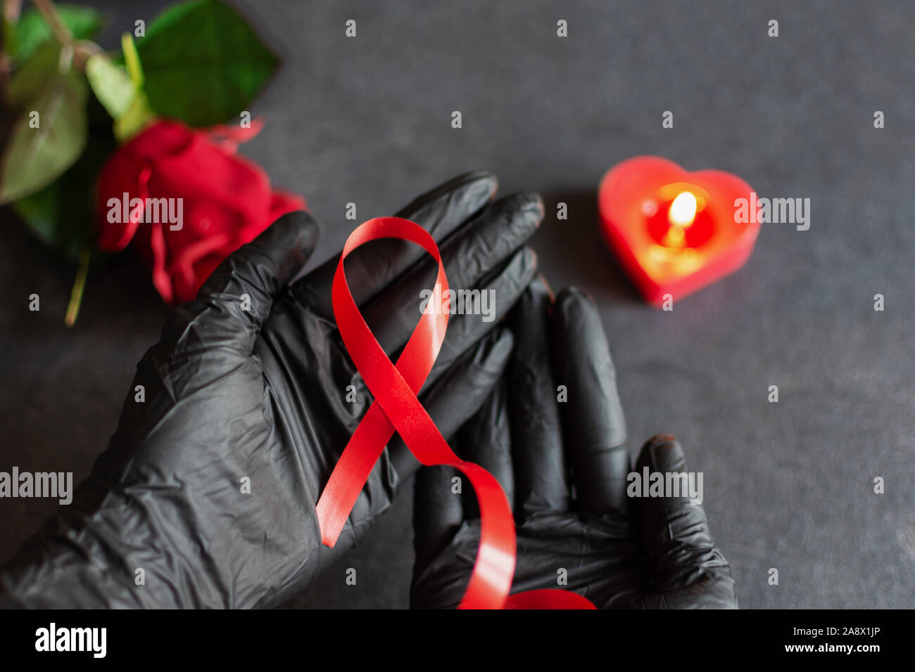 Female hand holding red ribbon as a symbol of World aids day December 1, campaign help people ...