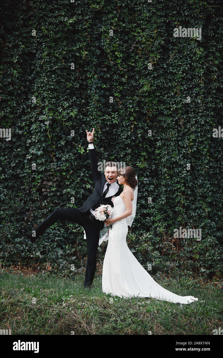 fun and crazy brides. happy gorgeous bride and stylish groom jumping ...