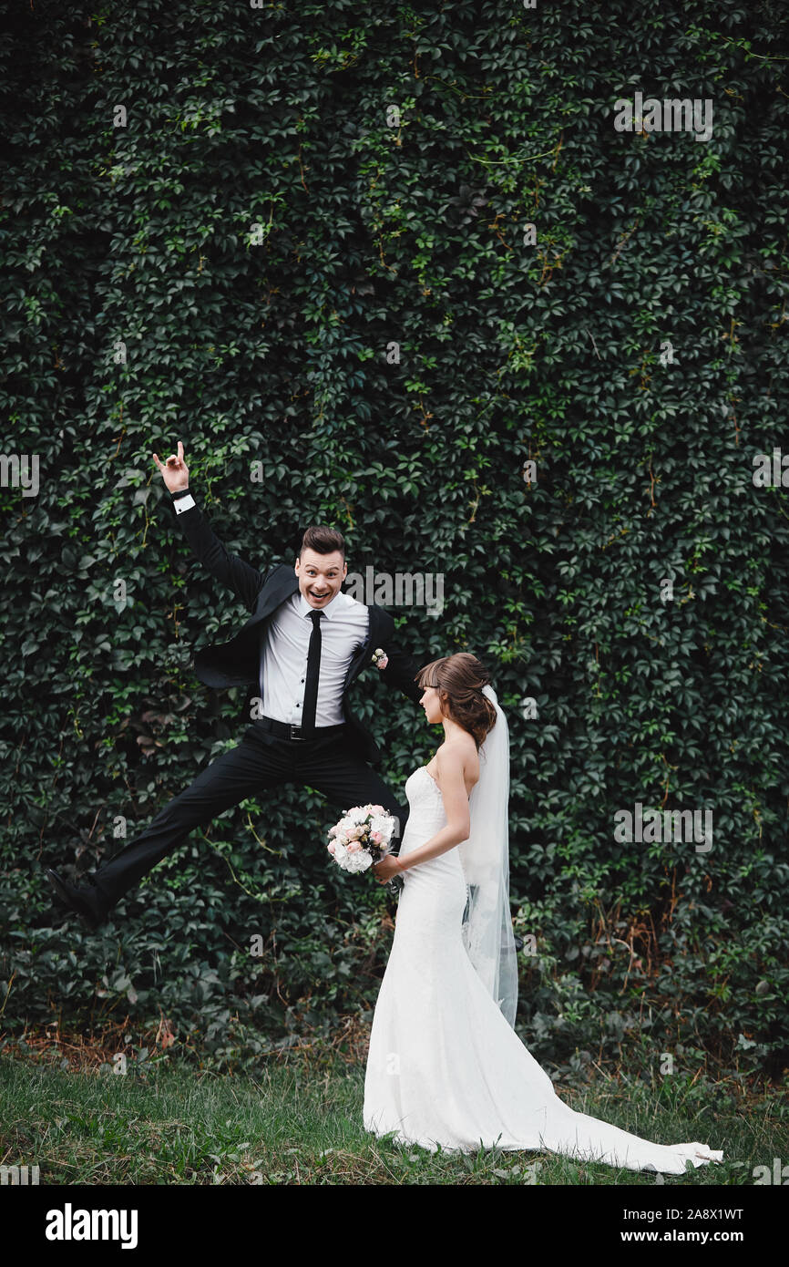 fun and crazy brides. happy gorgeous bride and stylish groom jumping ...