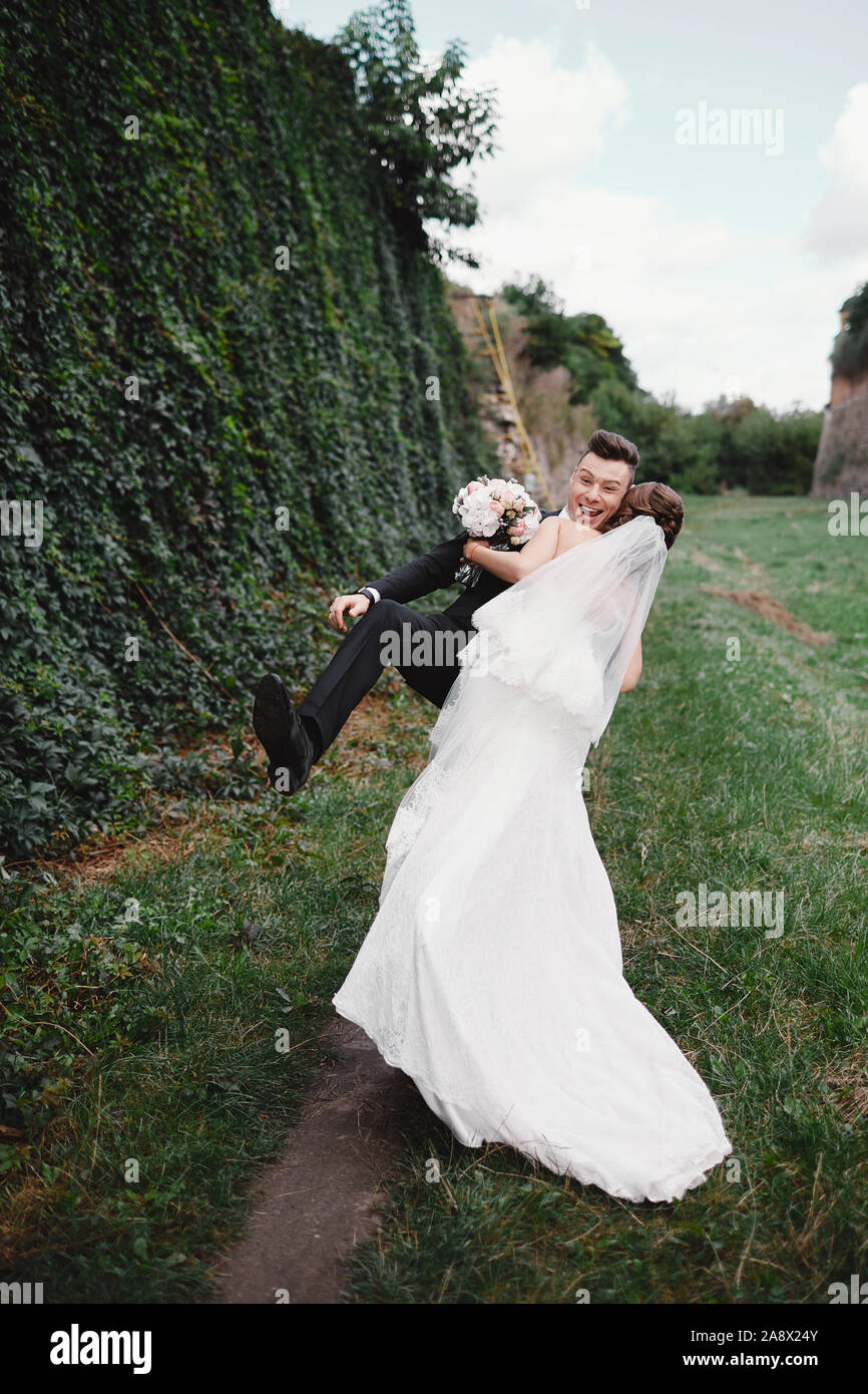 fun and crazy brides. happy gorgeous bride and stylish groom jumping ...