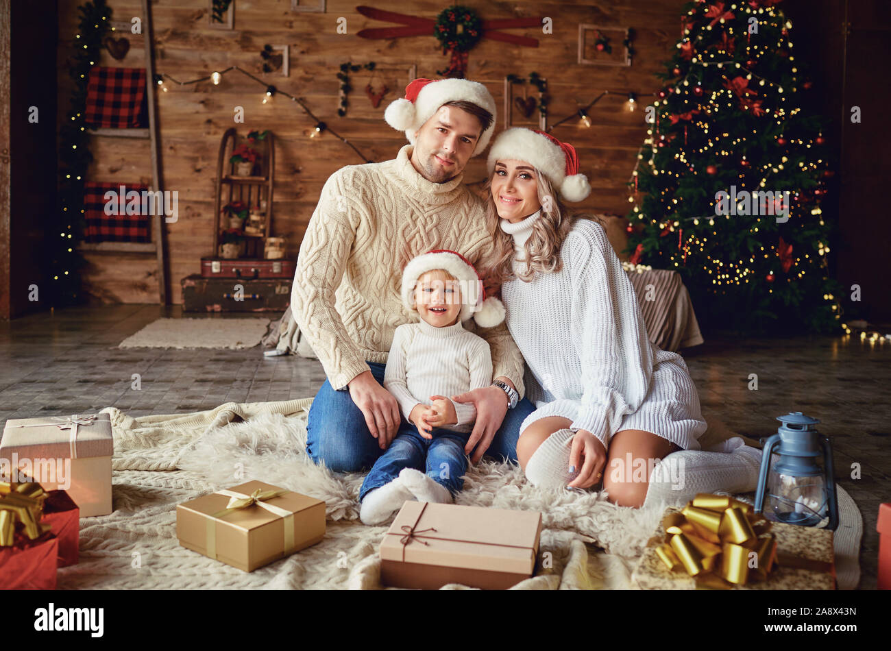 Family smiling at home with christmas tree Stock Photo - Alamy