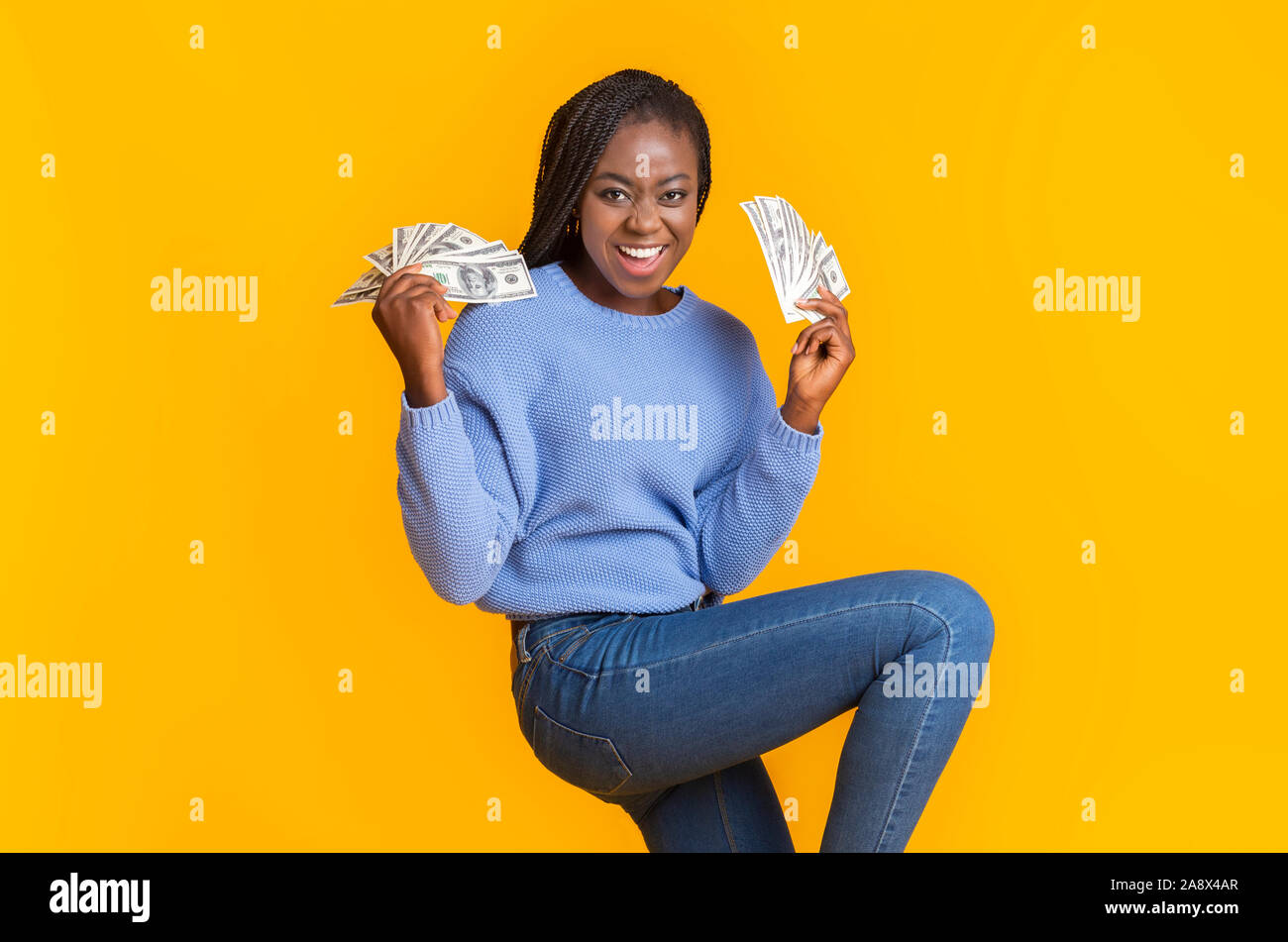 Extremely happy young black woman holding money in both hands Stock ...