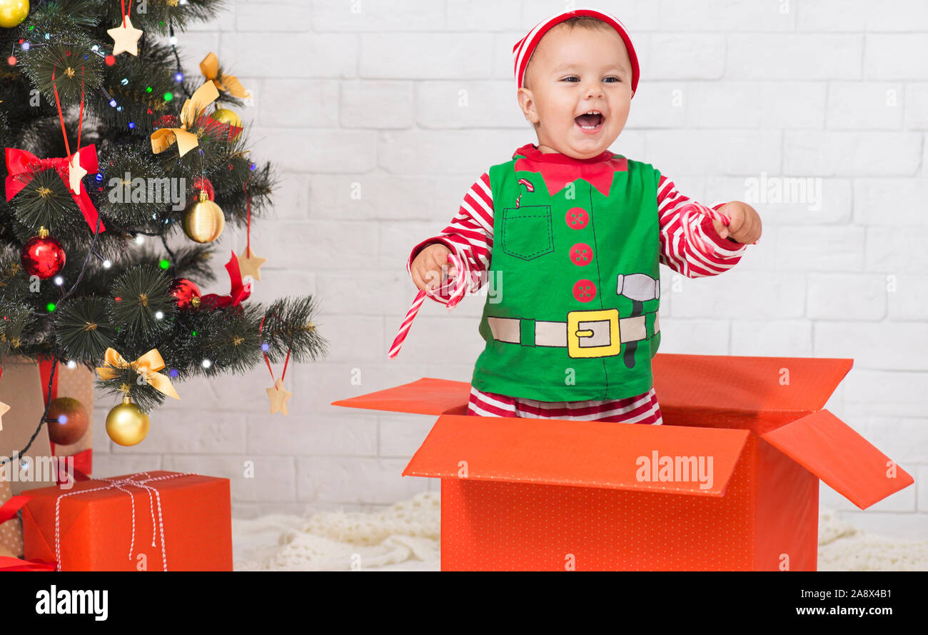 Cheerful baby elf with lollipops laughing in big gift box Stock Photo ...