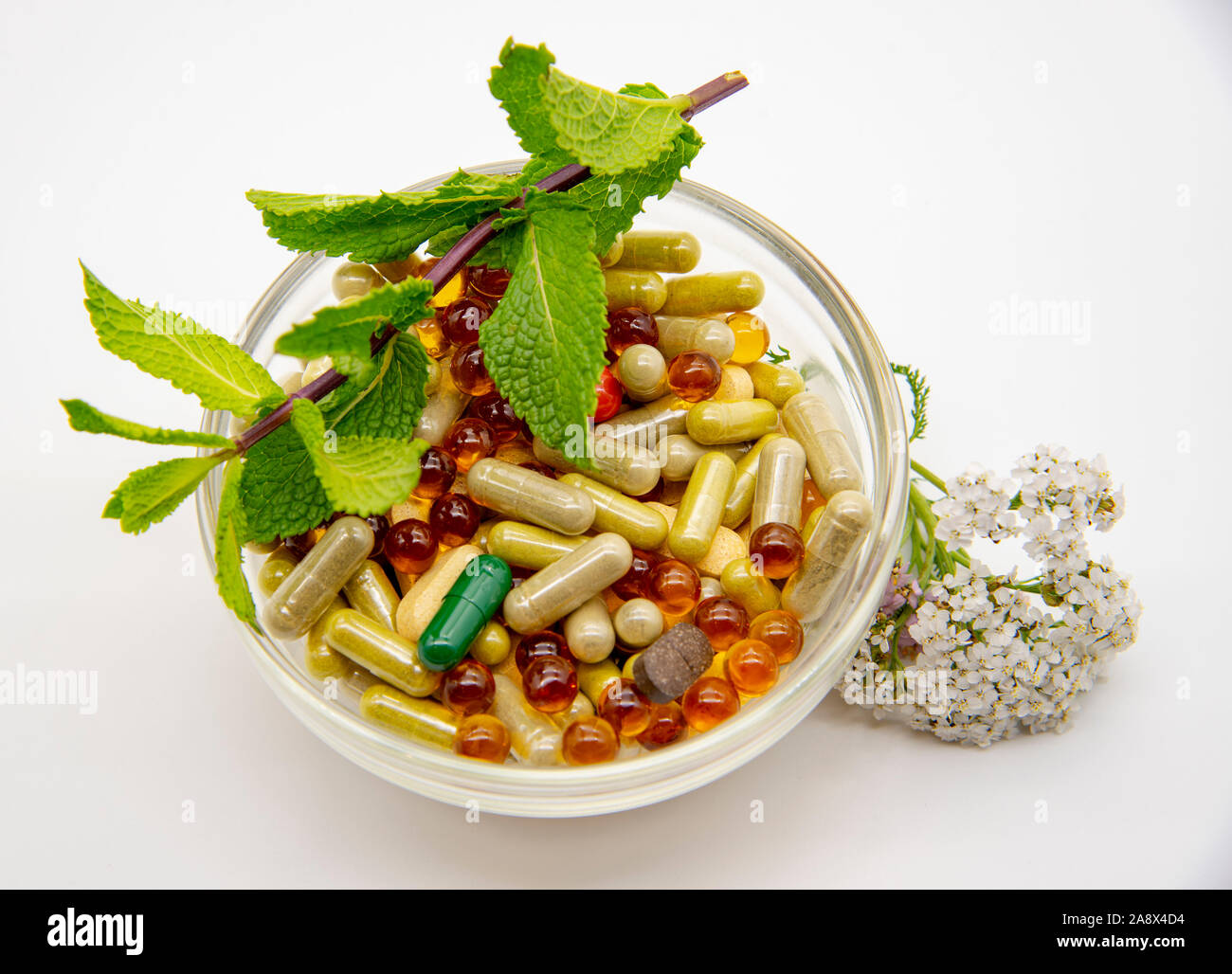 A bowl with various capsules and tablets, medicinal and aromatic herbs ...