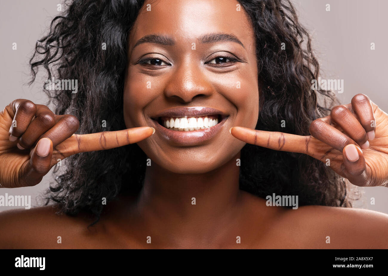 Happy black woman pointing at her perfect white teeth Stock Photo - Alamy