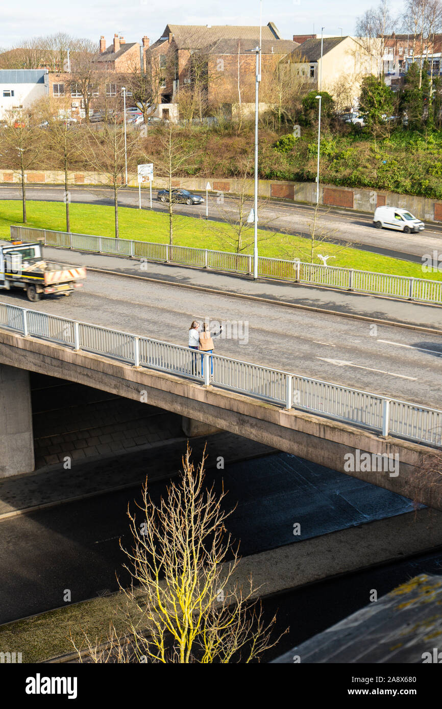 2 women take a selfie over looking a motorway bypass, attention posing ...
