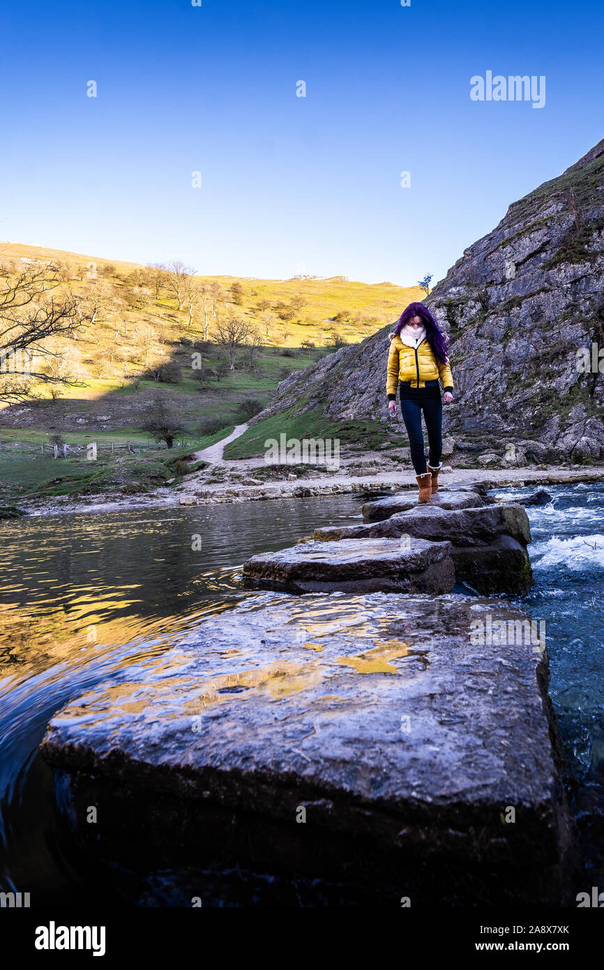 A pretty young athletic women crosses over the famous Dovedale stepping ...