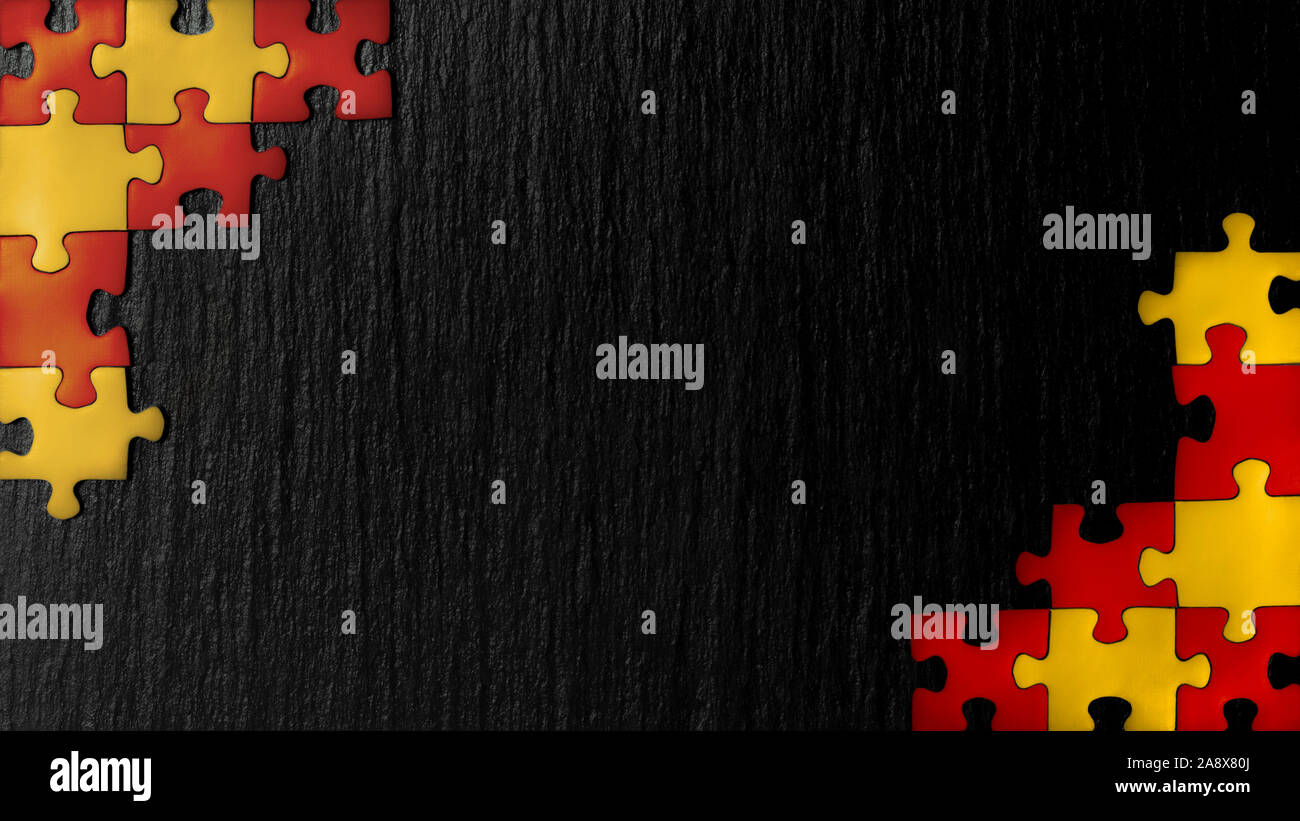 Red and yellow puzzles in the corners on a black slate stone background ...