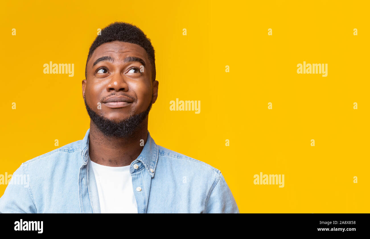 Cynical guy looking upwards at copy space on yellow background Stock ...
