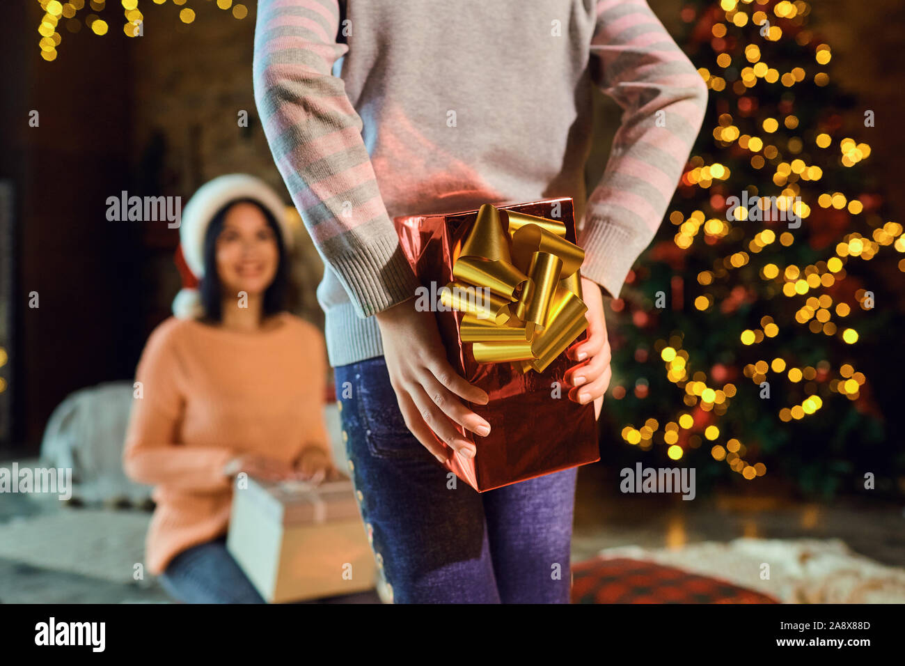 Girl hiding gift behind back while in Christmas Stock Photo - Alamy
