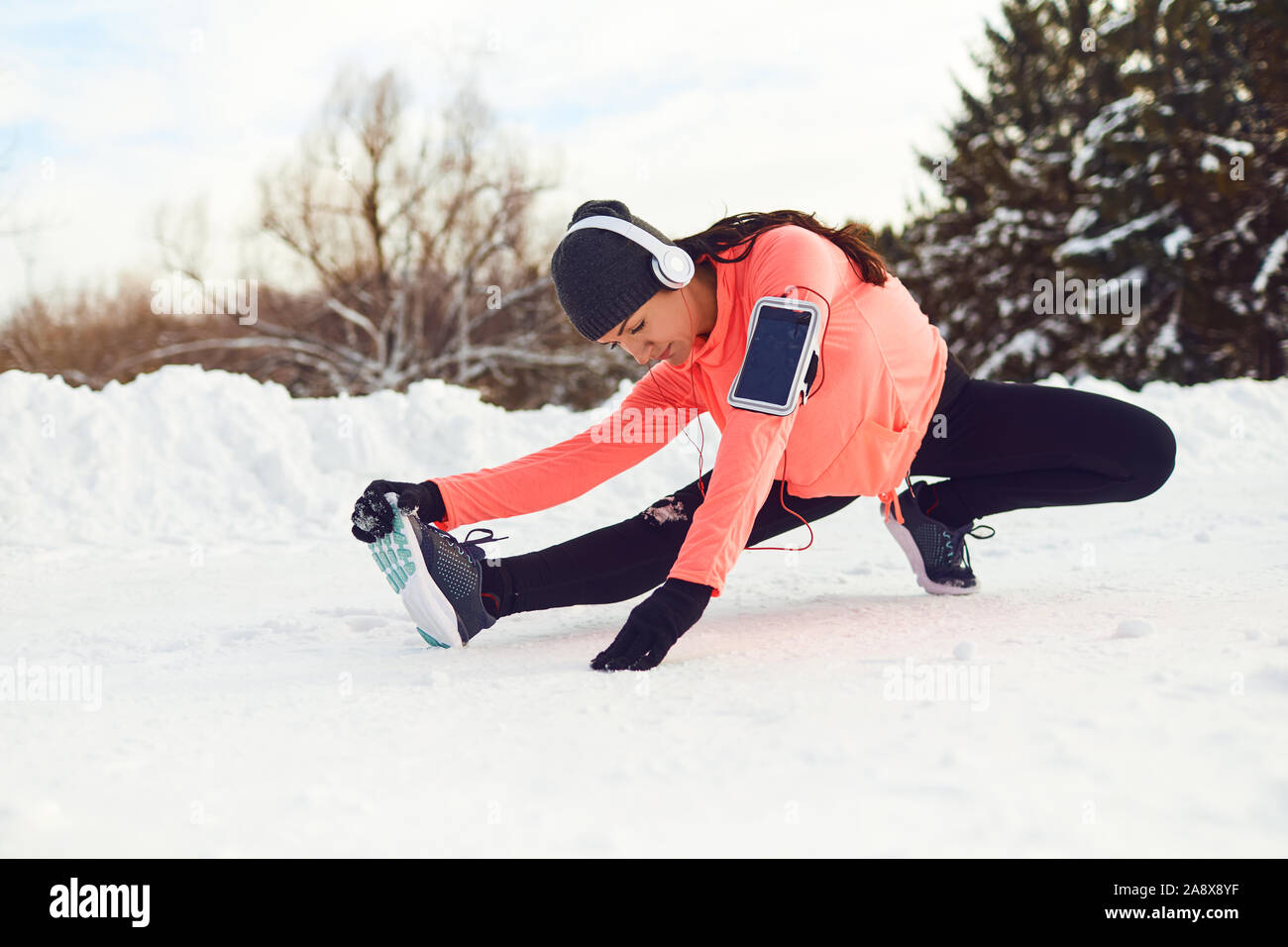 Girl athlete does stretching legs on the snow in winter Stock Photo - Alamy