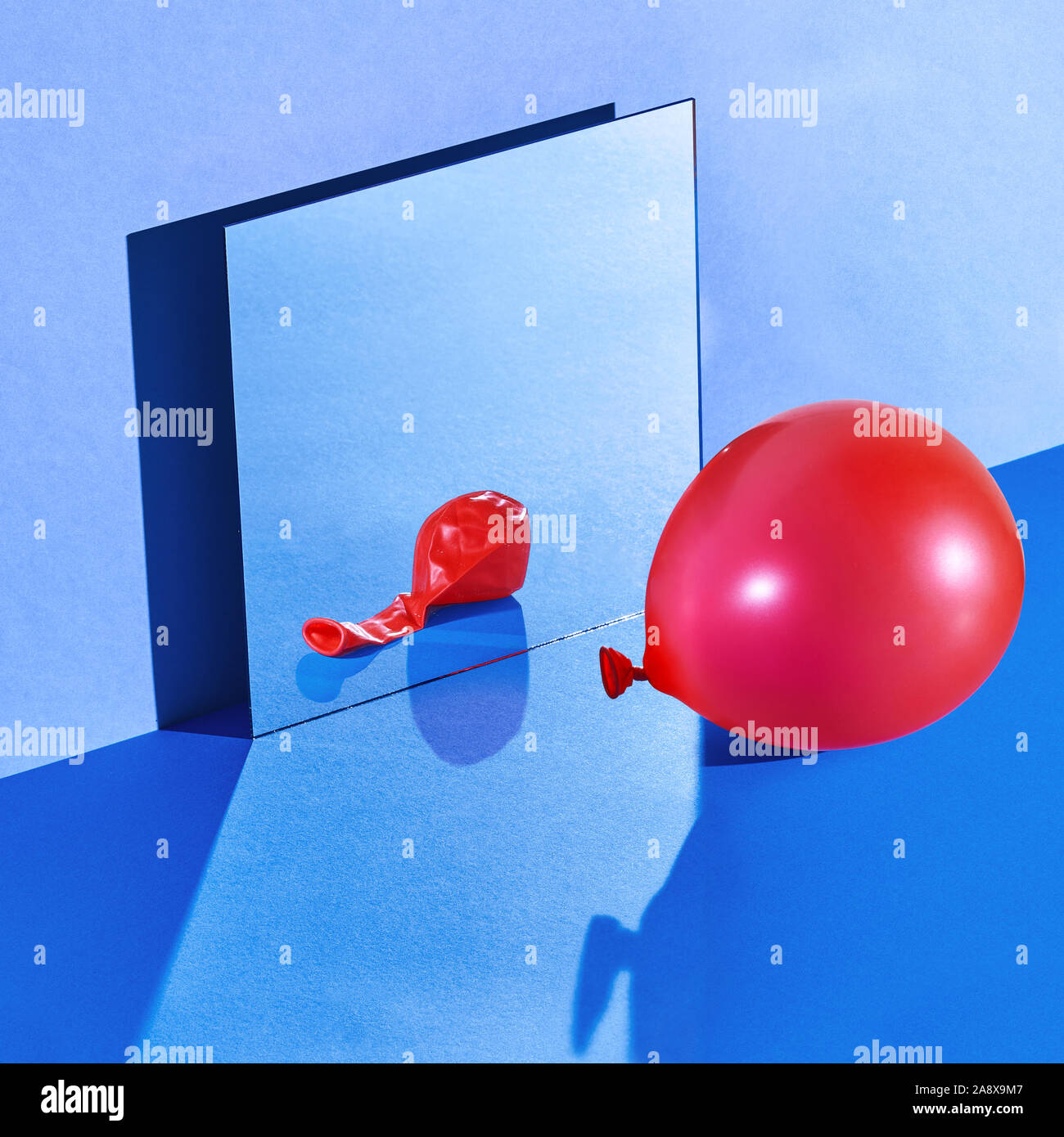 Still life space with a swollen balloon reflected on a deflated state ...